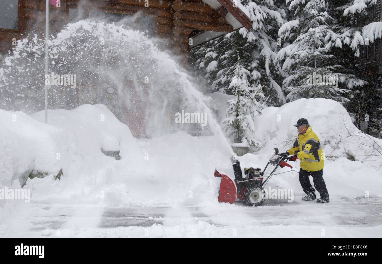 A man clearing snow with a mechanical snow blower. Whistler BC, Canada ...