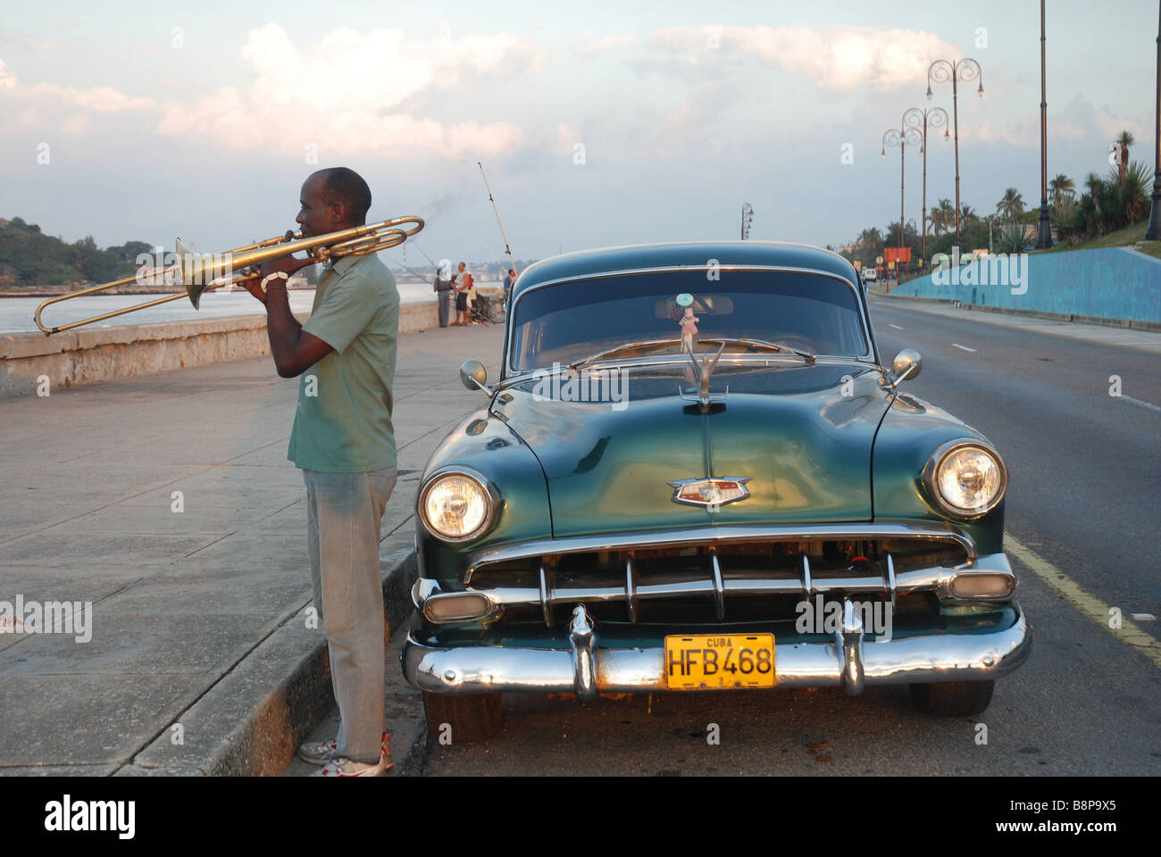Afro-Cuban musician playing the trombone by classic car. Havana, Cuba ...