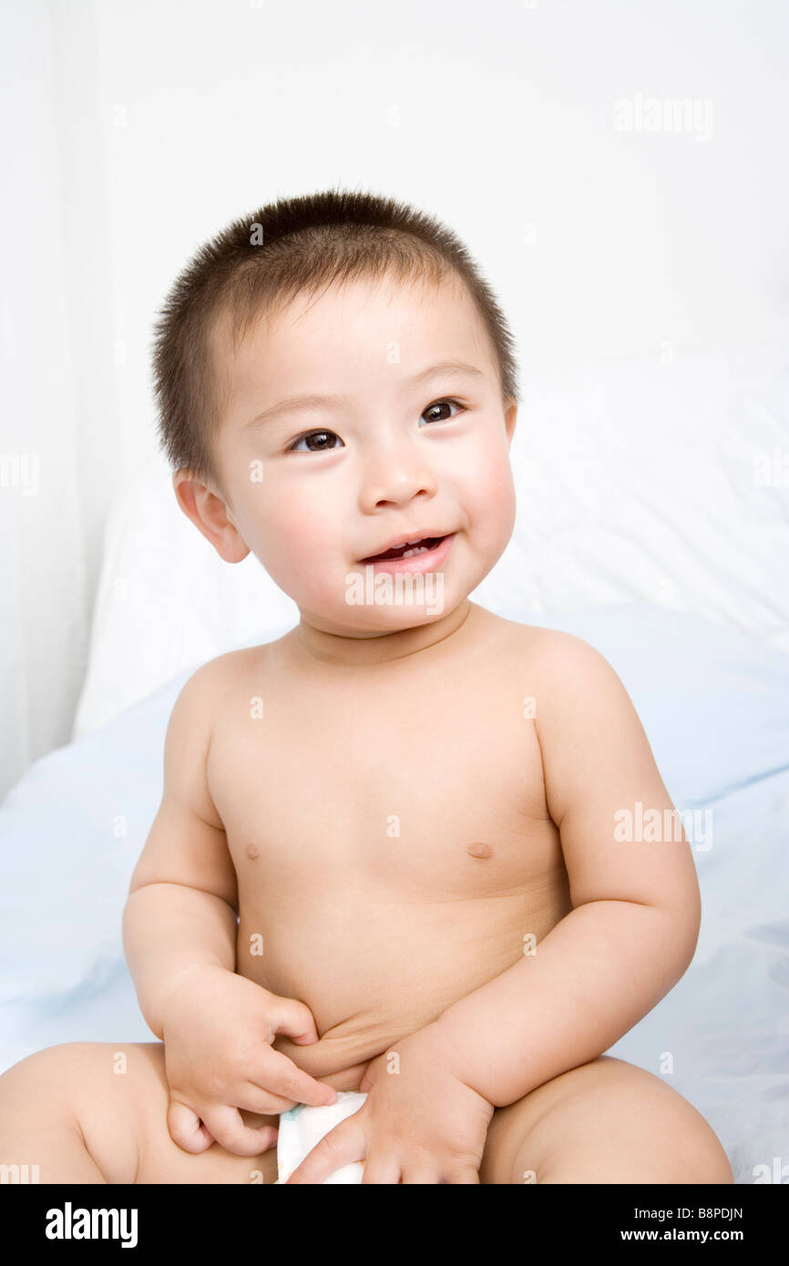Baby boy sitting on bed smiling portrait Stock Photo - Alamy