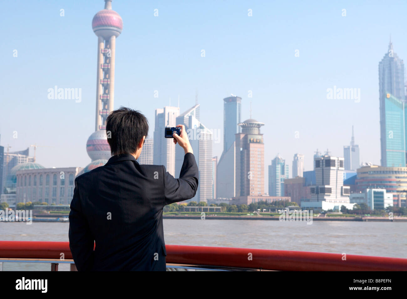 Young businessman taking picture by rail rear view Stock Photo - Alamy