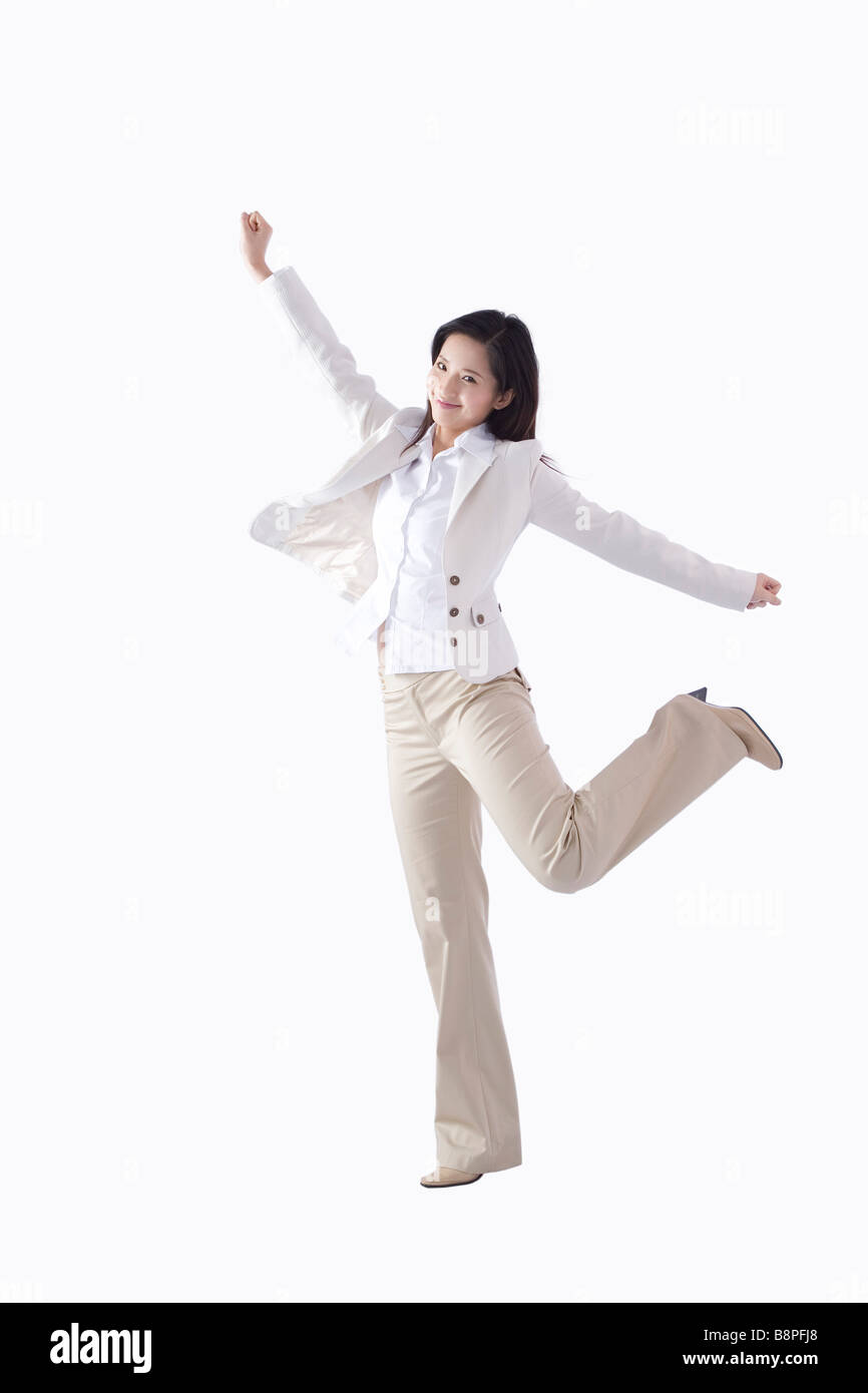 Young businesswoman standing on one leg making a gesture smiling side ...