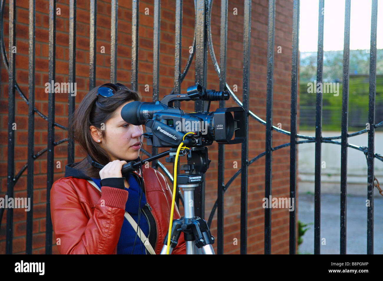 Young woman with video camera on tripod filming Stock Photo - Alamy