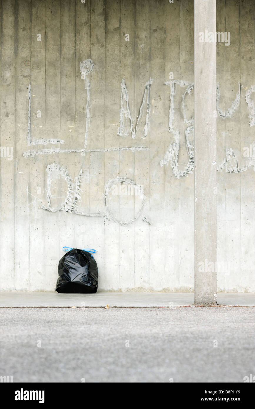Bag of garbage leaning against wall Stock Photo - Alamy