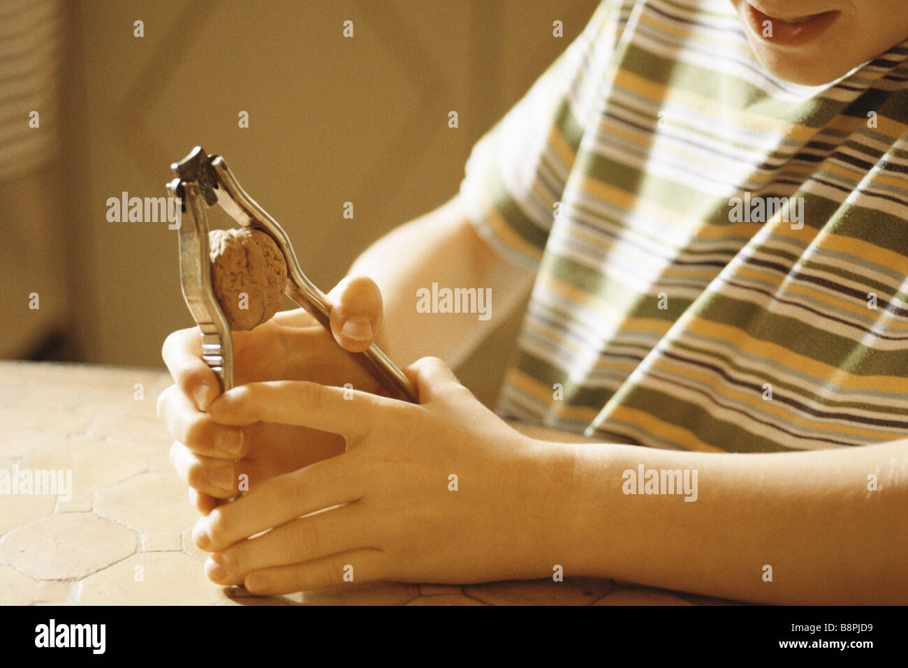 Boy trying to crack walnut Stock Photo - Alamy