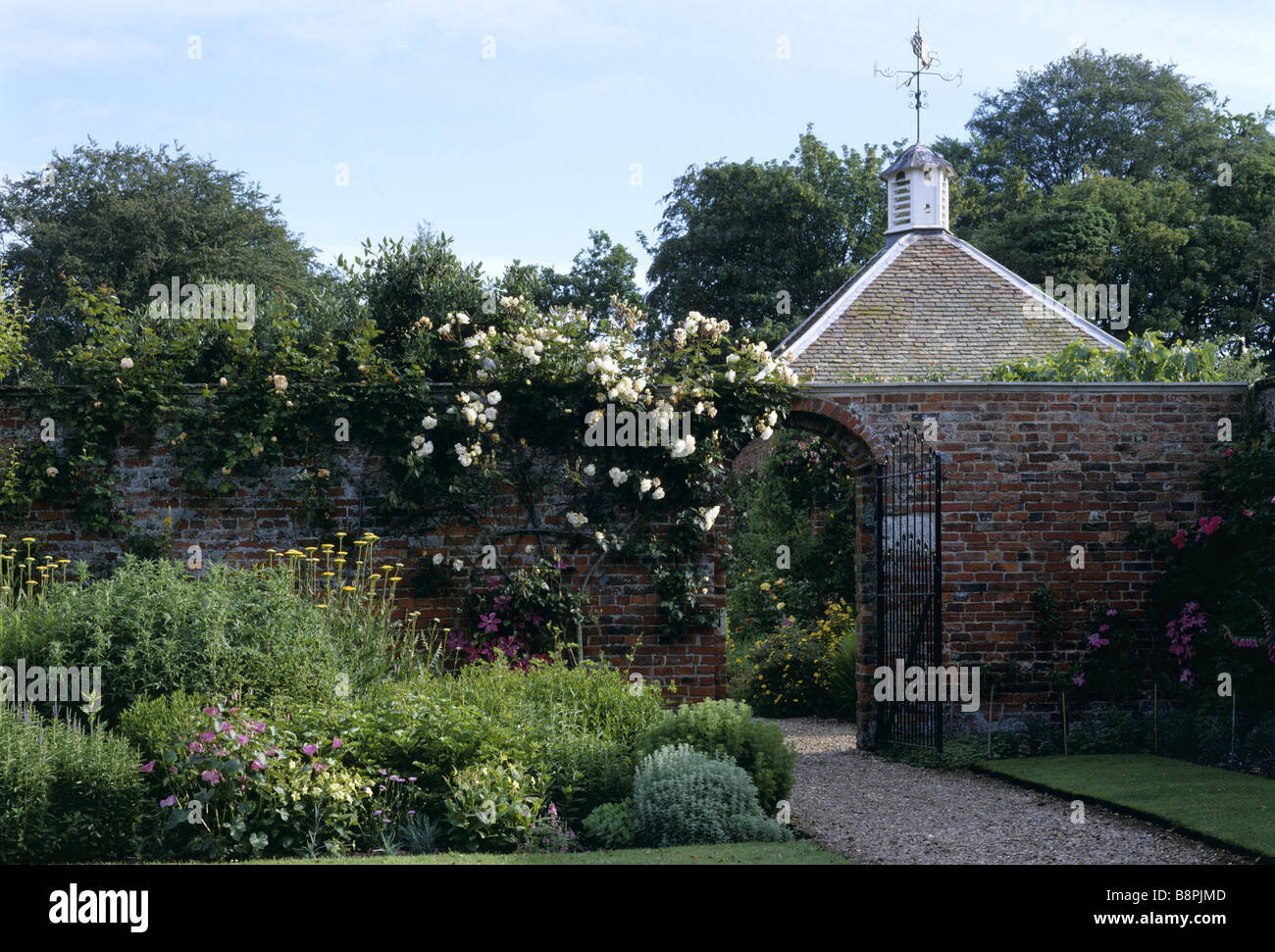 The Garden at Gunby Hall in June with white roses overhanging a brick ...