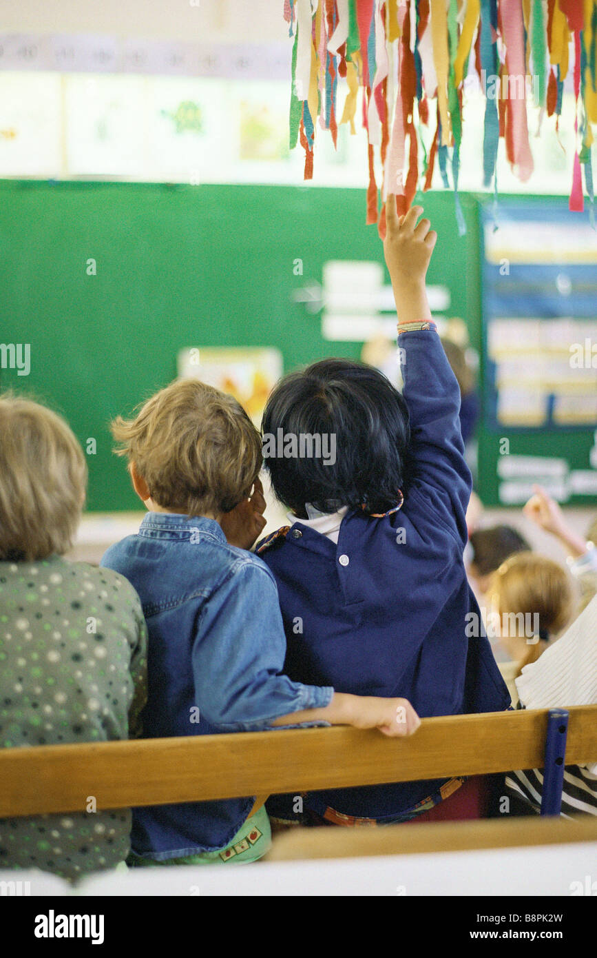 Child raising hand in class, rear view Stock Photo - Alamy