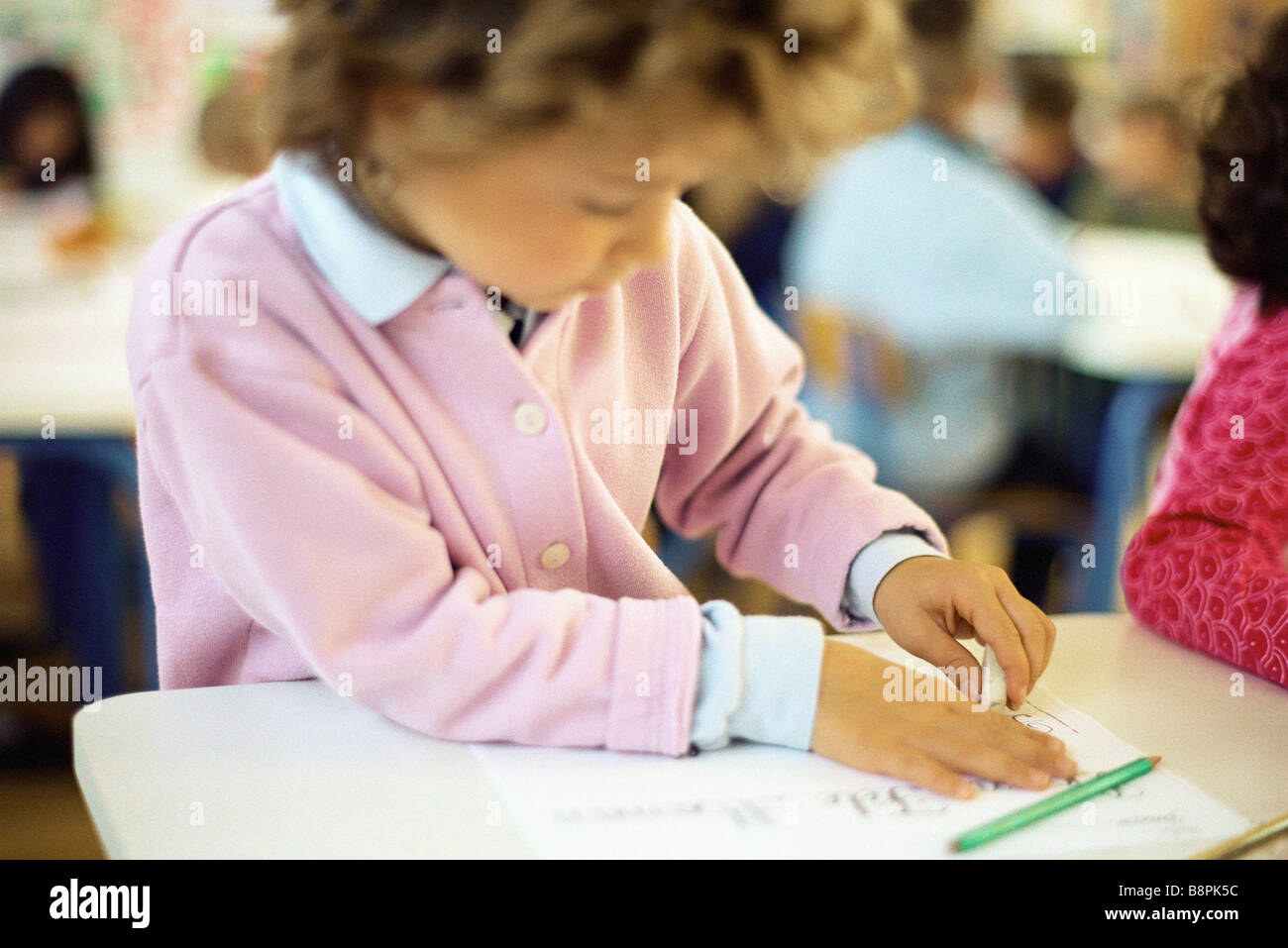 Girl sitting at desk, erasing writing Stock Photo - Alamy