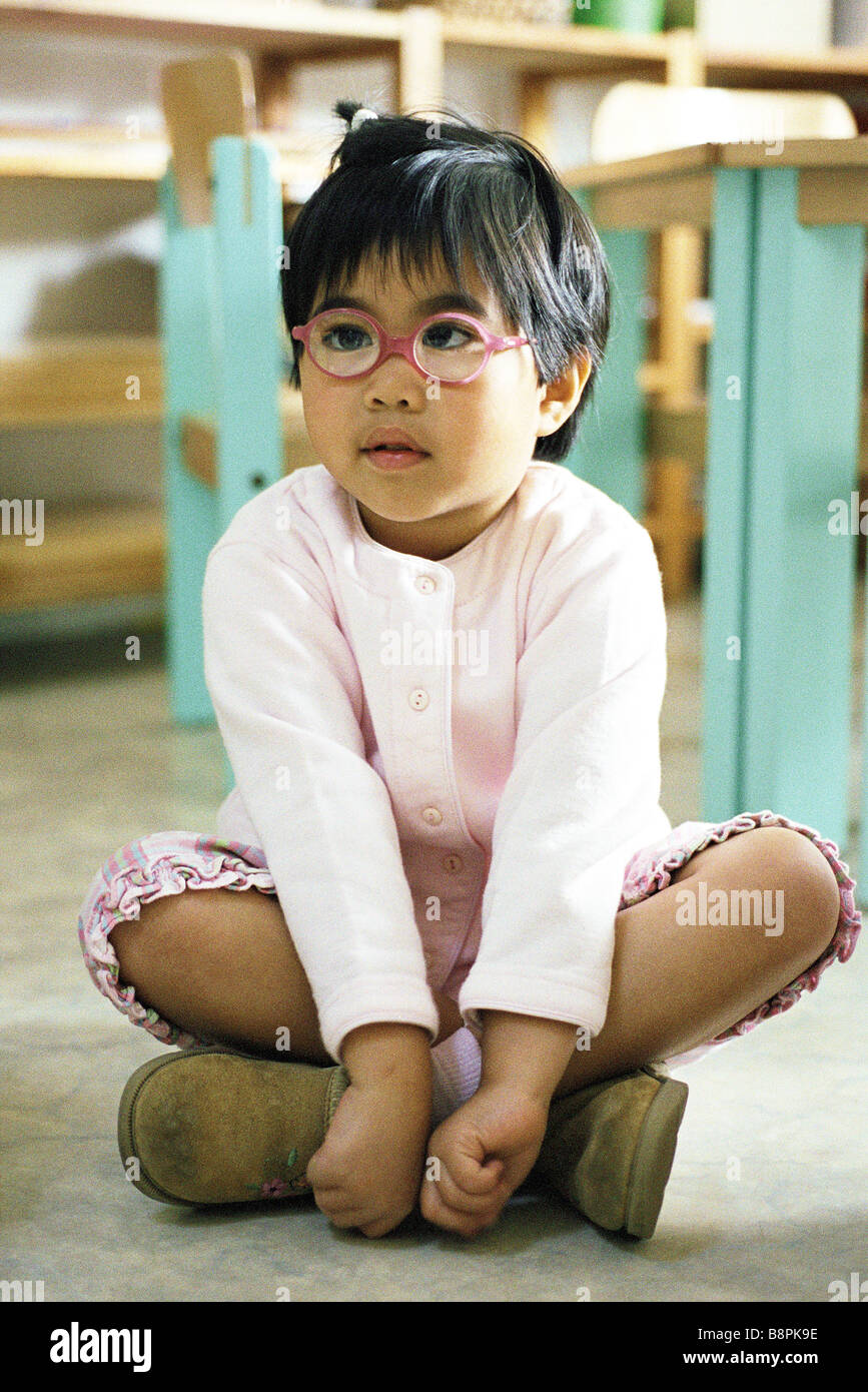 Little girl sitting indian style on floor Stock Photo - Alamy