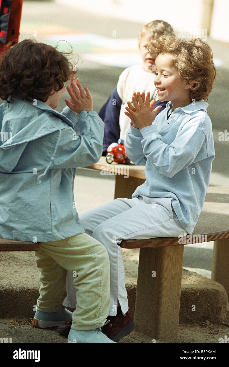 Girls playing clapping game on bench Stock Photo - Alamy