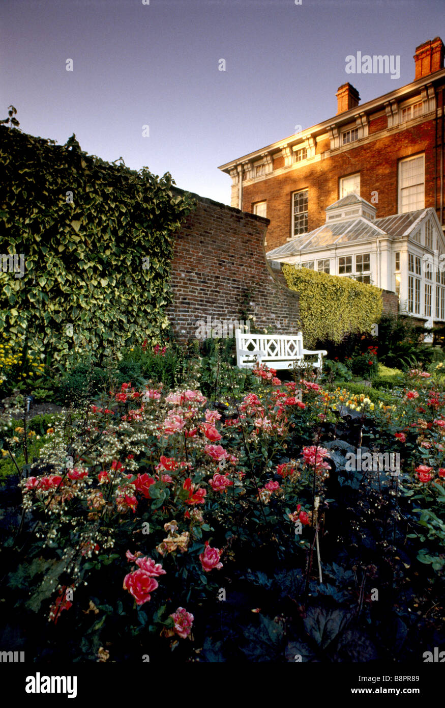 Exterior of the house and conservatory from the garden with pink roses ...