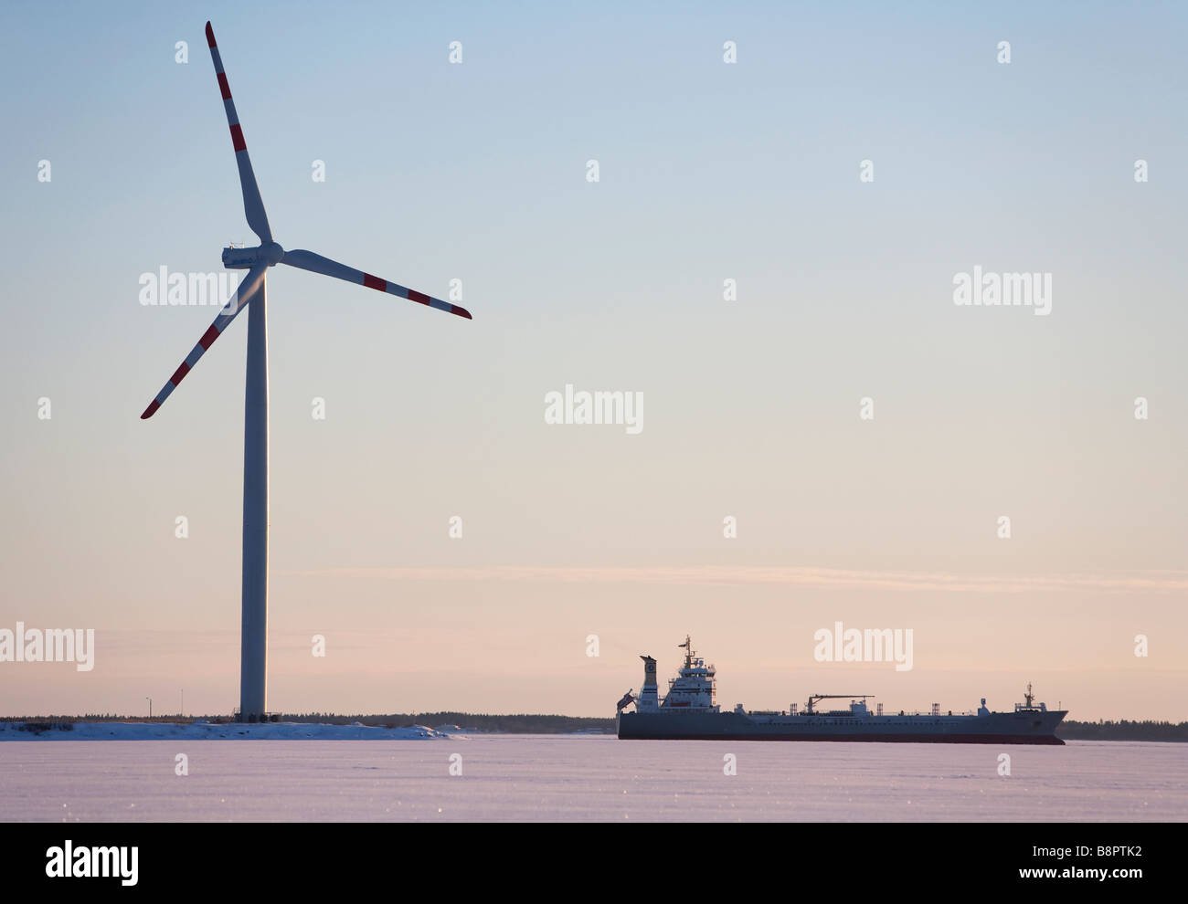 Cargo ship on frozen sea passing a big WinWind 3 MW wind turbine , Oulu ...