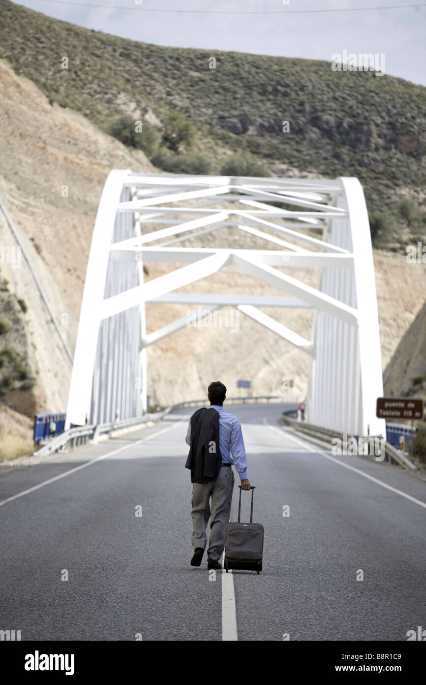 Man dresses in suit walks along a road towards a bridge Stock Photo - Alamy