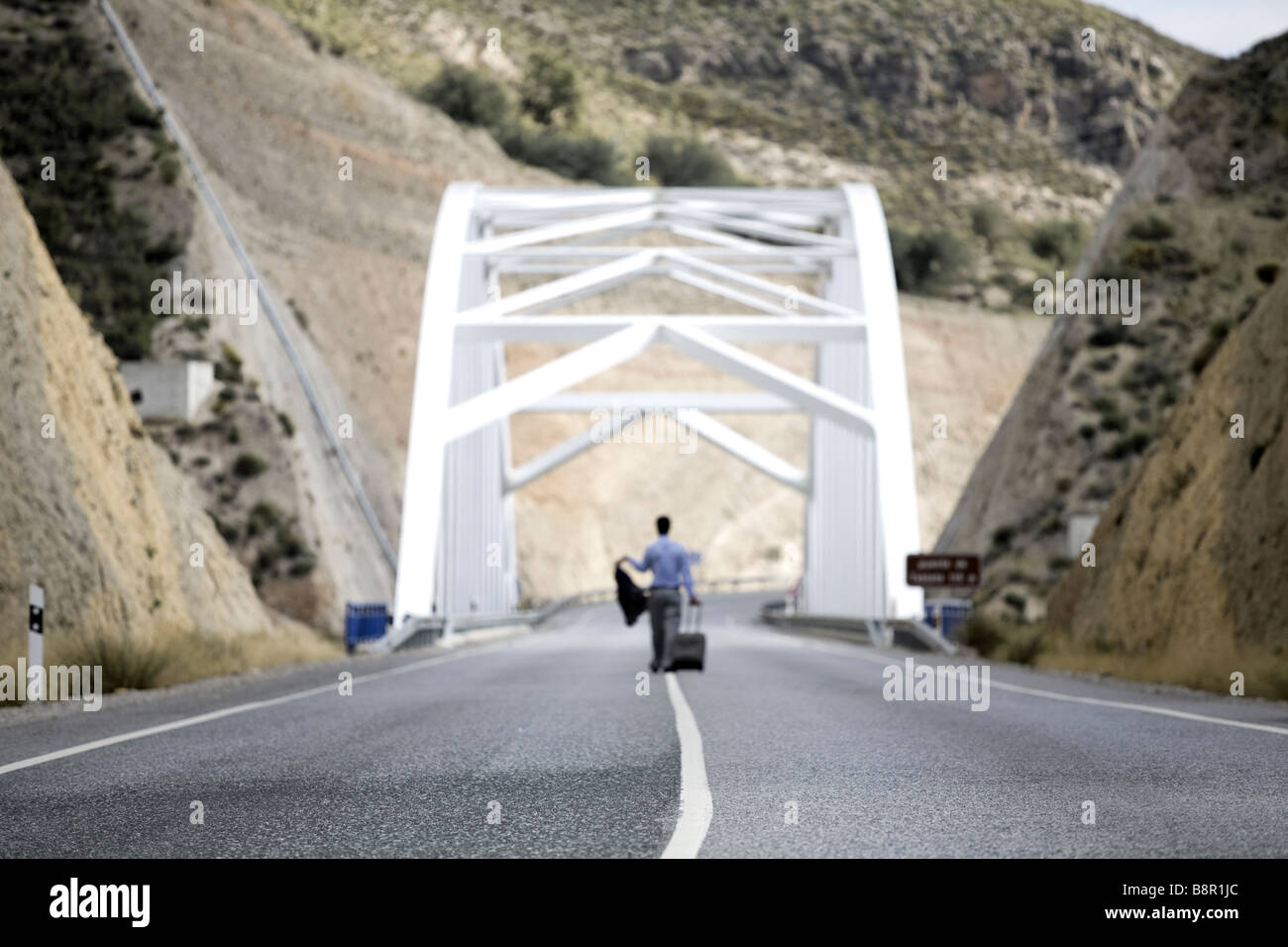 Man dresses in suit walks along a road towards a bridge Stock Photo - Alamy