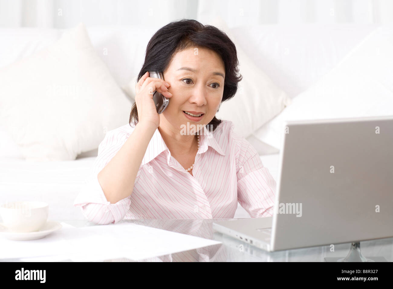 Senior woman on the phone looking laptop Stock Photo - Alamy