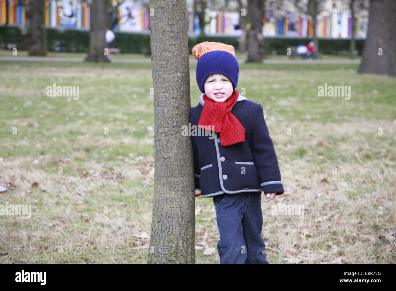 little smiling boy leaning on a tree in a park Stock Photo - Alamy