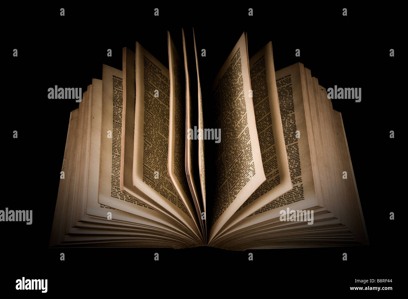 Old encyclopaedia lying open, black background Stock Photo - Alamy