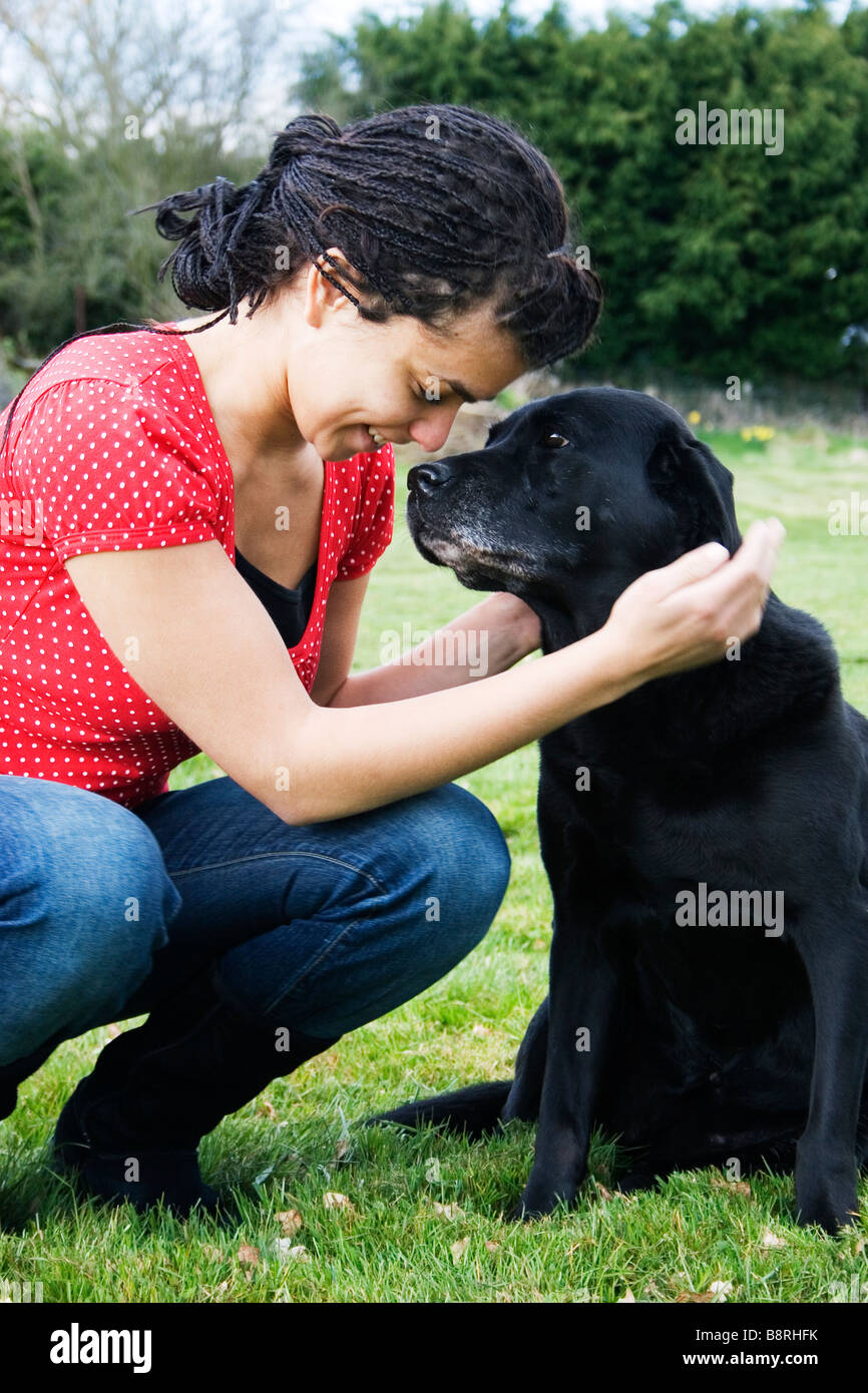 teenage girl making fuss of elderly black labrador in garden Stock ...