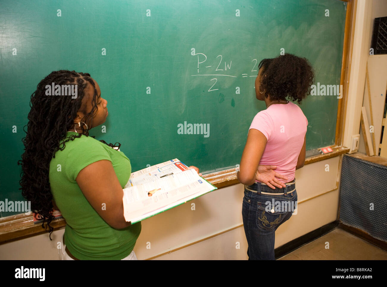 two teenage girls test eachother on math problems in classroom, middle ...