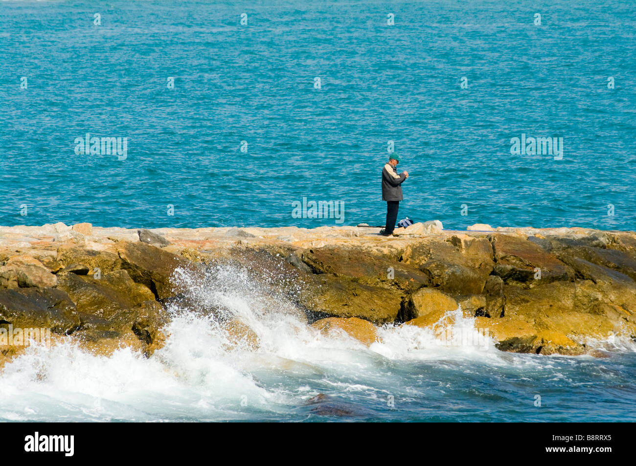 Angler angling Fishing On a Rocky Outcrop In The Mediterranean Sea ...