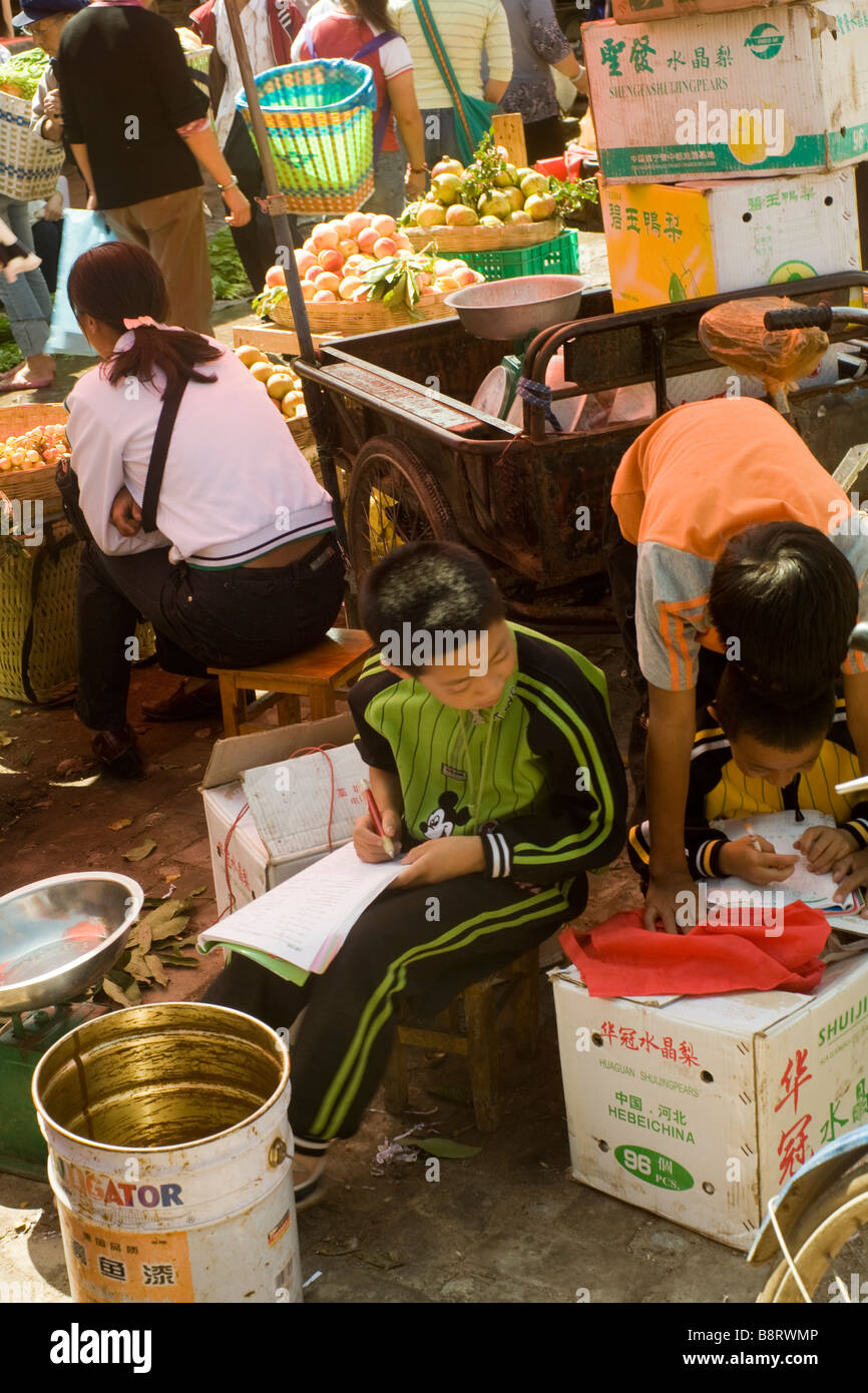 Chinese schoolboys doing homework on a market stall in Lijiang, Yunnan ...