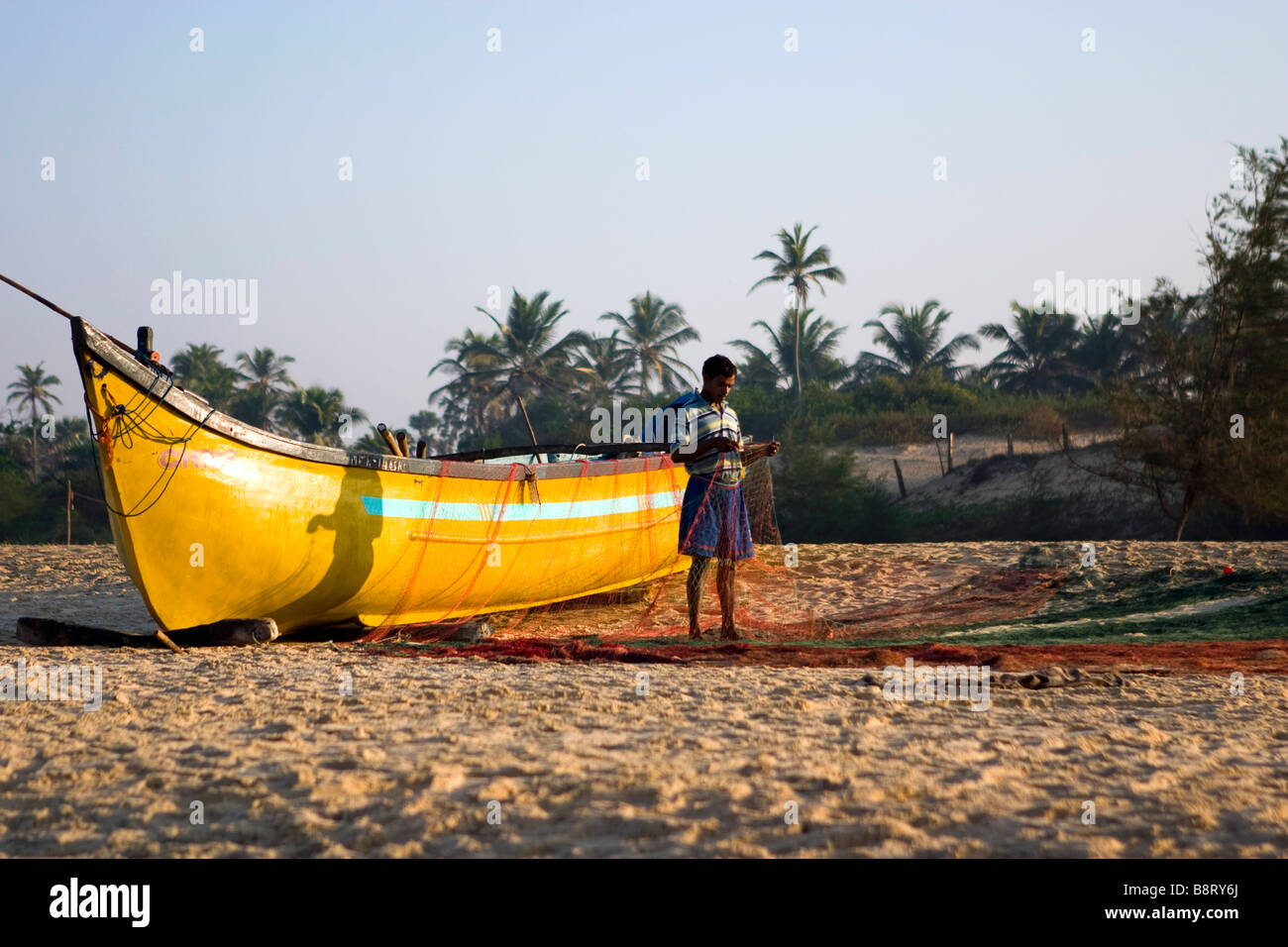 Fisherman patching holes in net on Varca beach,Goa,India Stock Photo ...