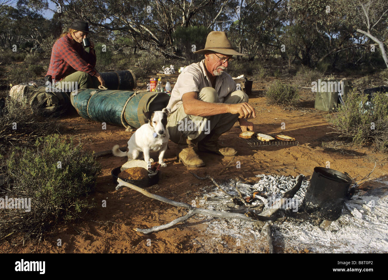 man sitting next to a campfire in the australian outback, Australia ...