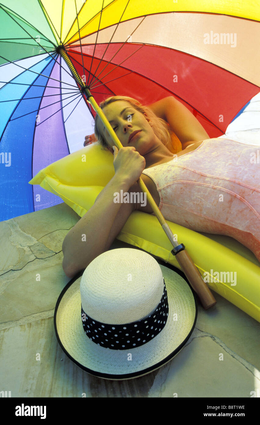 young woman lying under multicoloured sunshade Stock Photo - Alamy