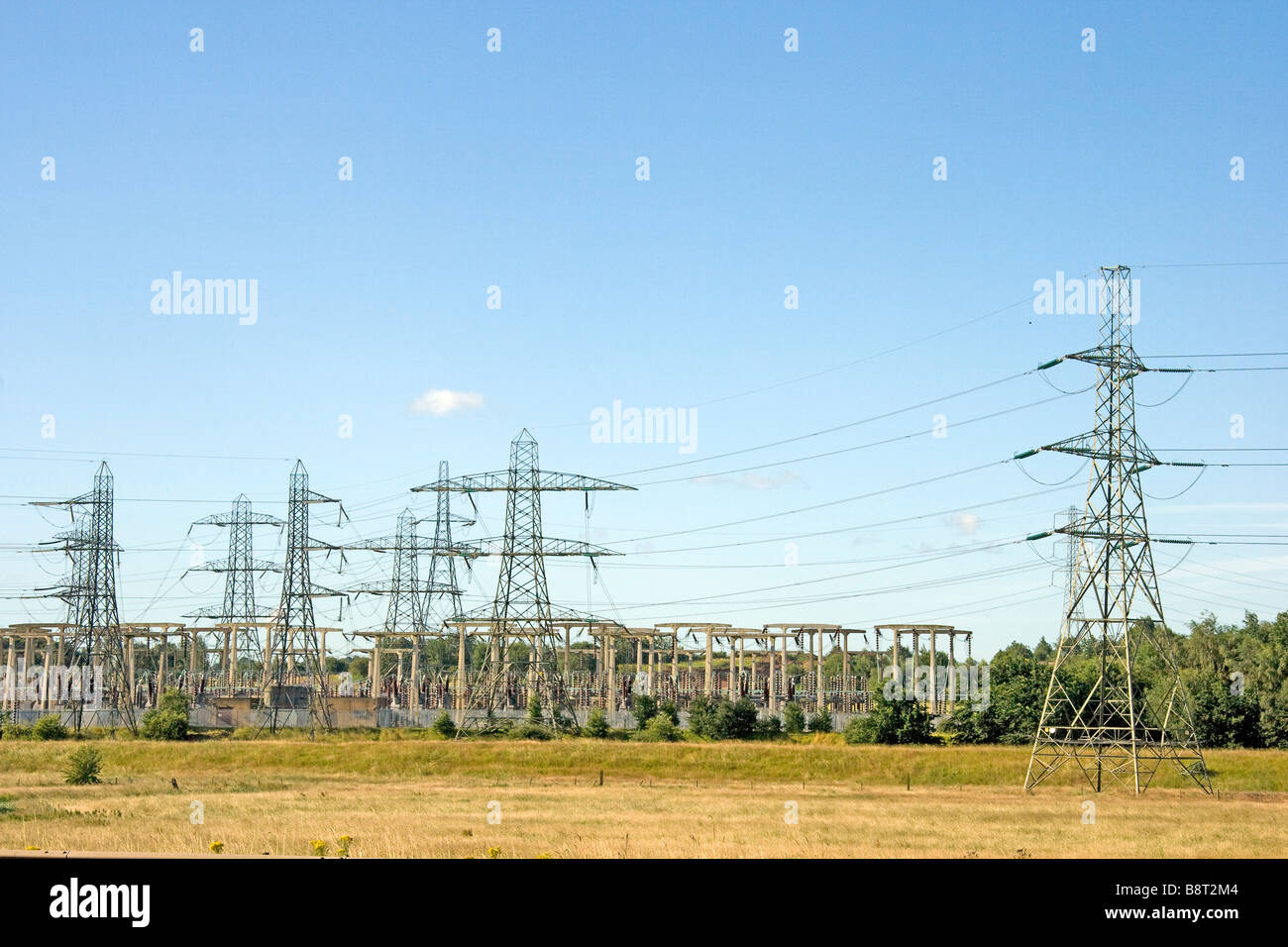 Electricity pylons and substation by a field in the sun Stock Photo - Alamy