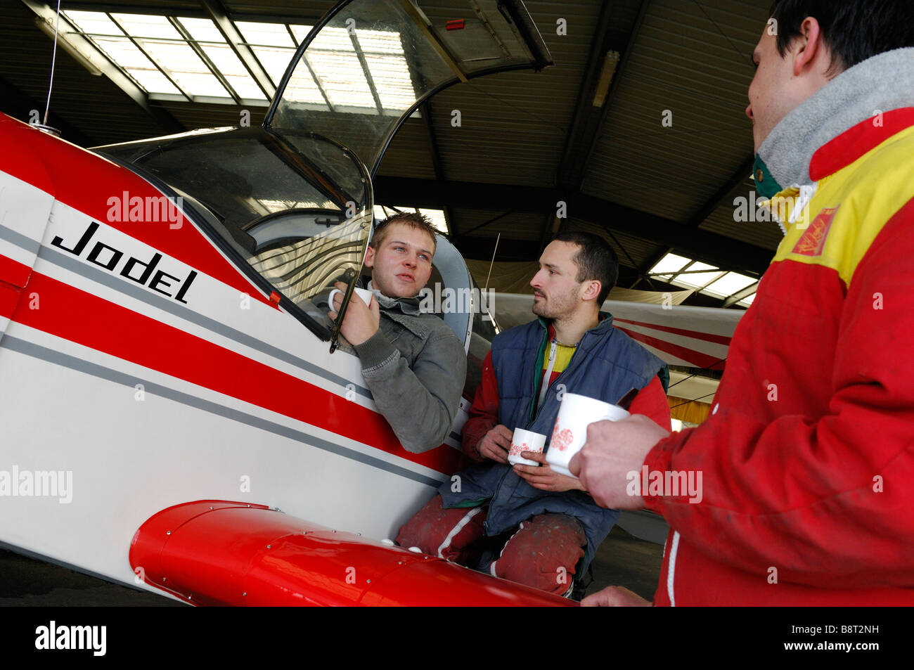 young french pilot and mecanic drinking a coffee in an hangar with old ...