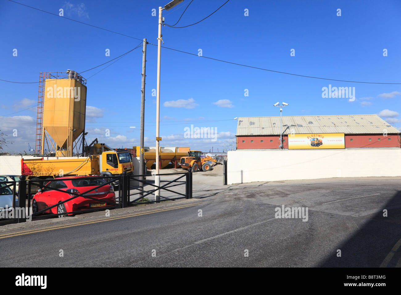 Red and Yellow Lorries in a Ready Mix Cement Yard on the River Thames ...