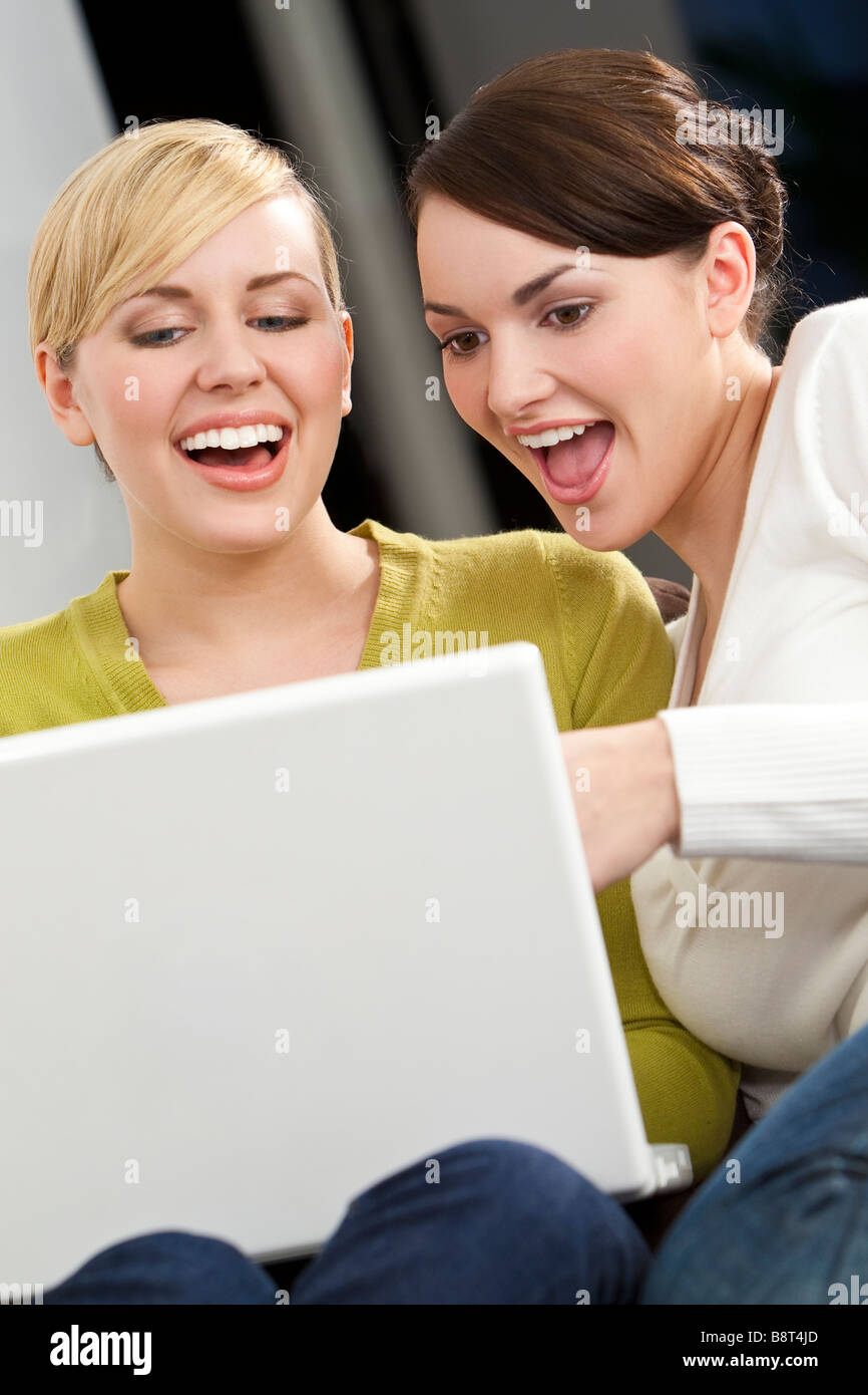 Two beautiful young women having fun on a white laptop computer Stock ...