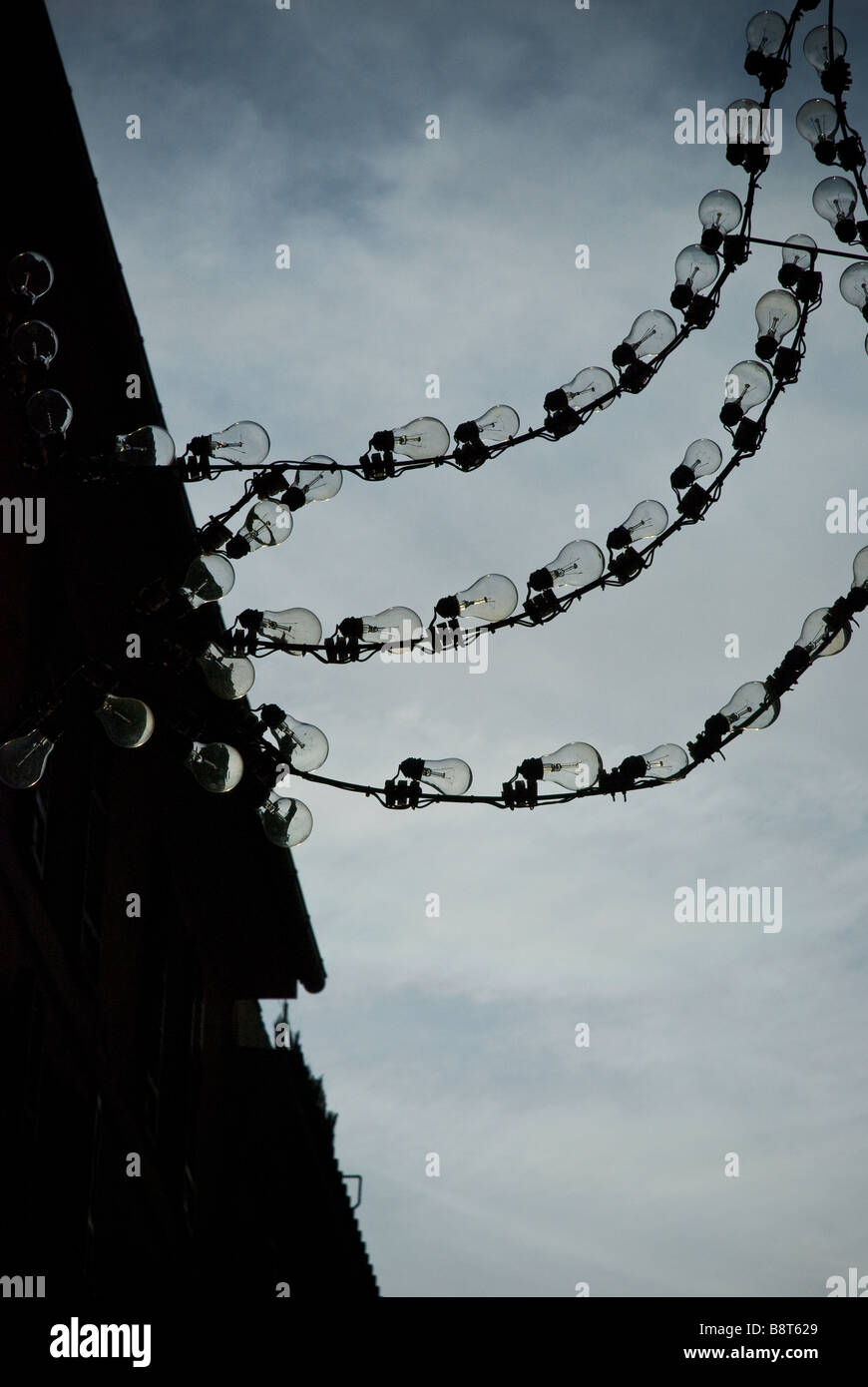 Several strings of lightbulbs are strung between buildings in Palma ...