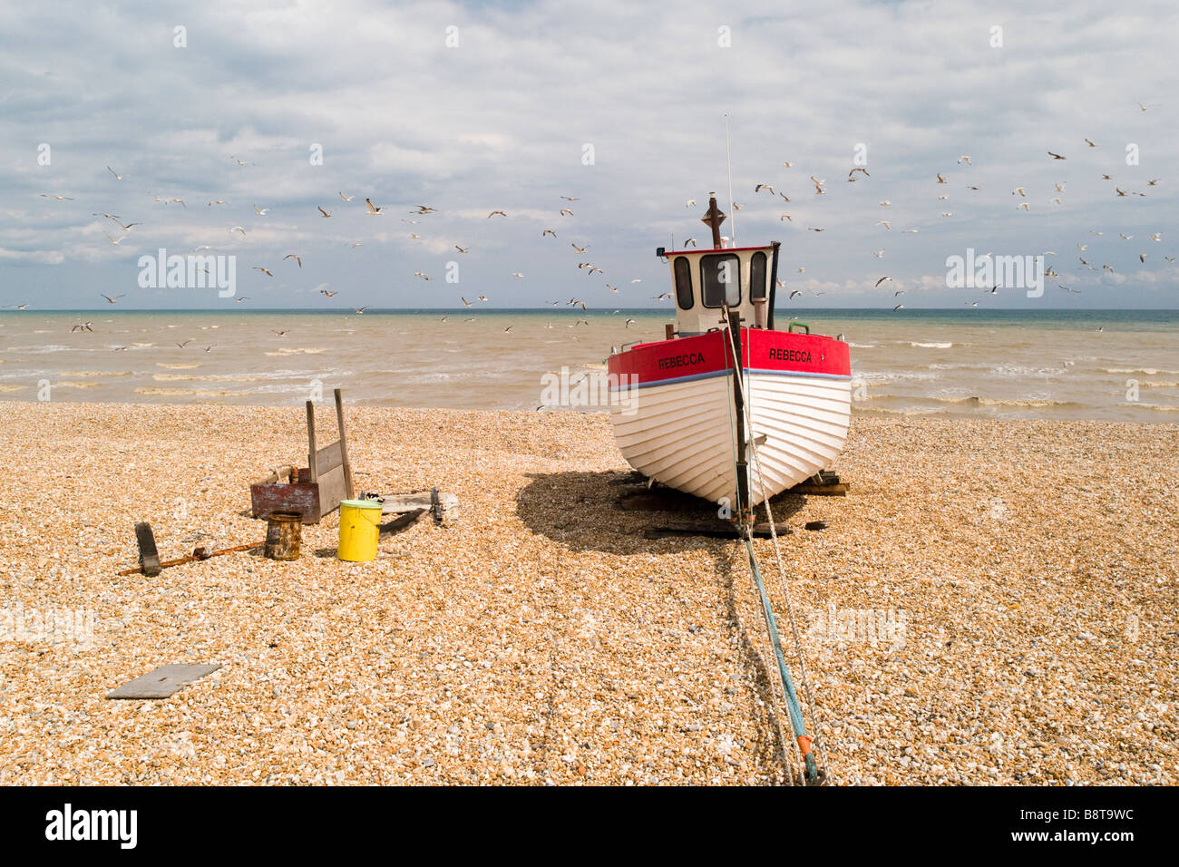 Clinker built fishing boat drawn up on the beach, in South East England ...