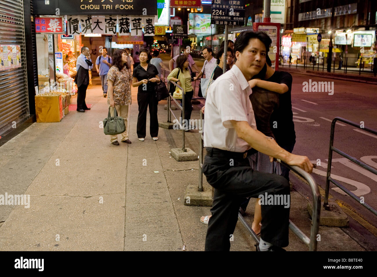 People waiting at a bus stop at night in Kowloon discrict of Hong Kong ...