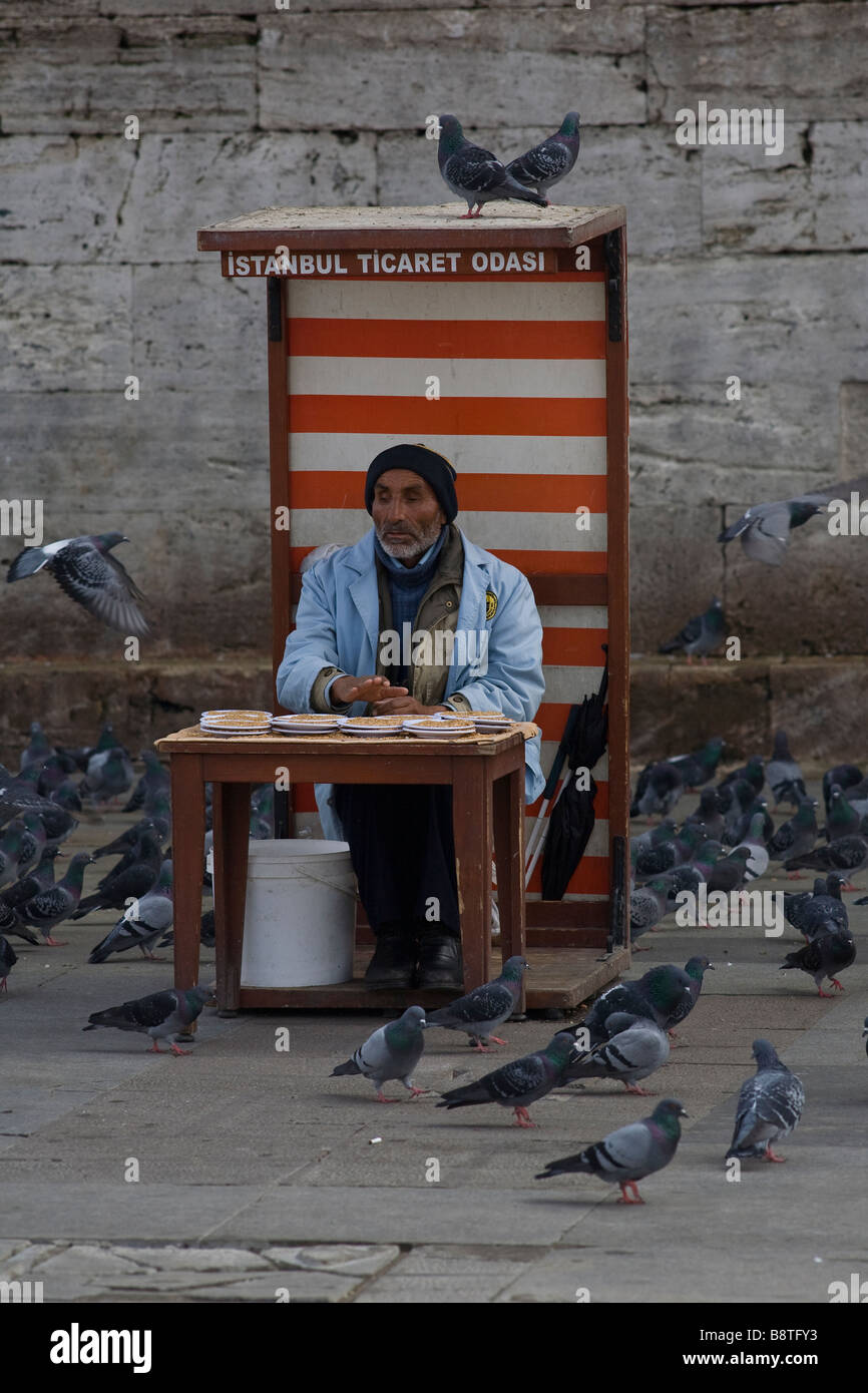 Ticket vendor fighting pigeons at the New Mosque in Turkey Istanbul ...