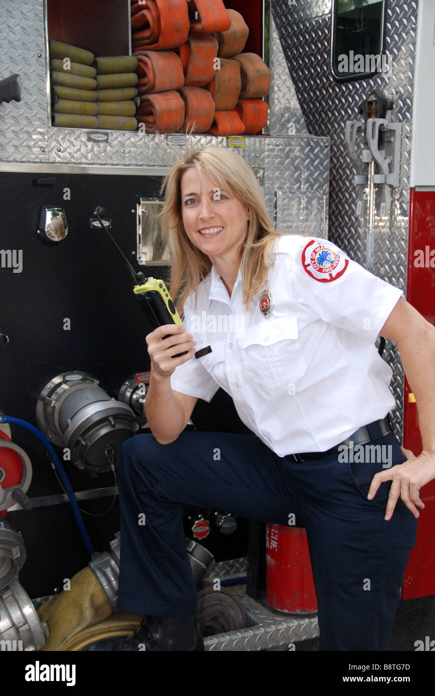 Smiling Female Firefighter Paramedic Emt In Dress Uniform Talking On Two Way Radio In Front Of