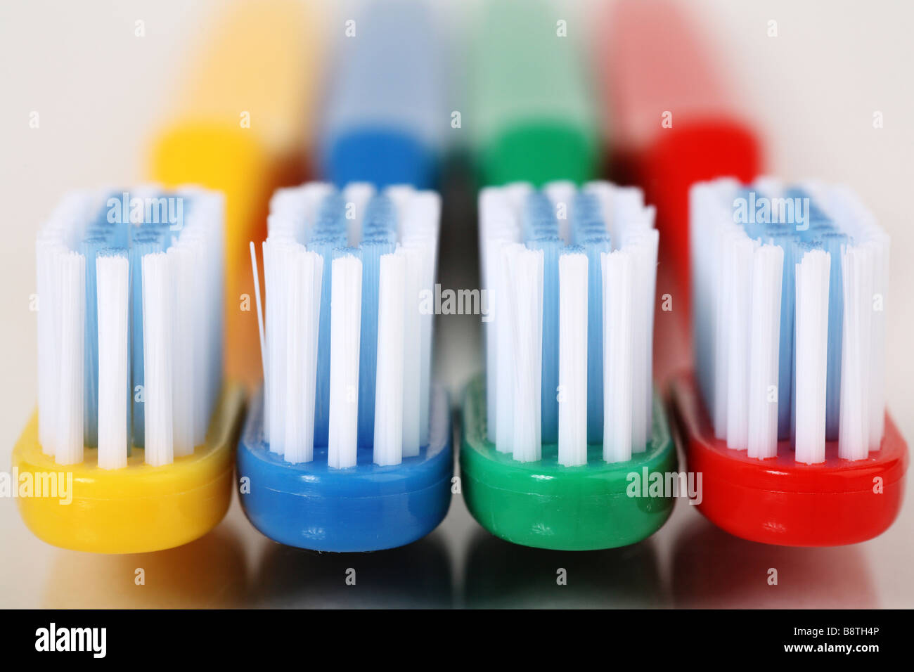 Row of four different coloured toothbrushes Stock Photo - Alamy
