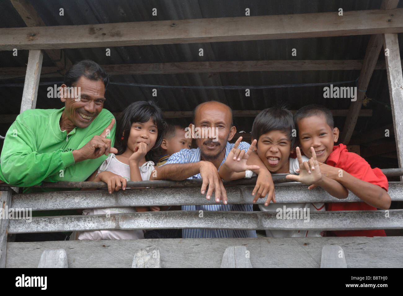 Suluk family in window of wooden house Pulau Bodgaya Semporna Sabah ...