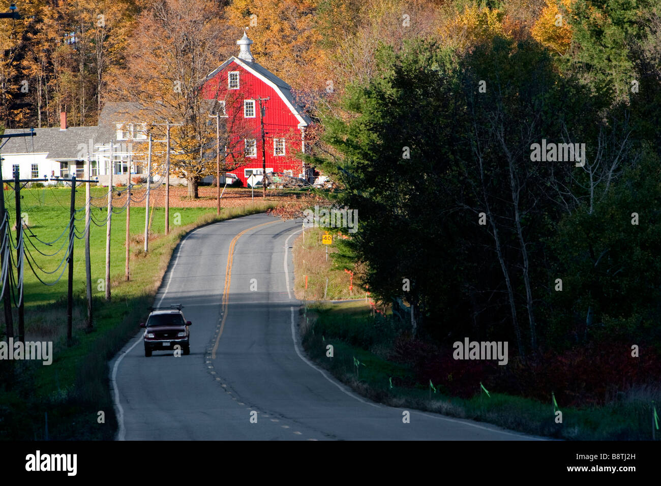 A road winds through trees near a barn in rural Vermont USA October 10 ...