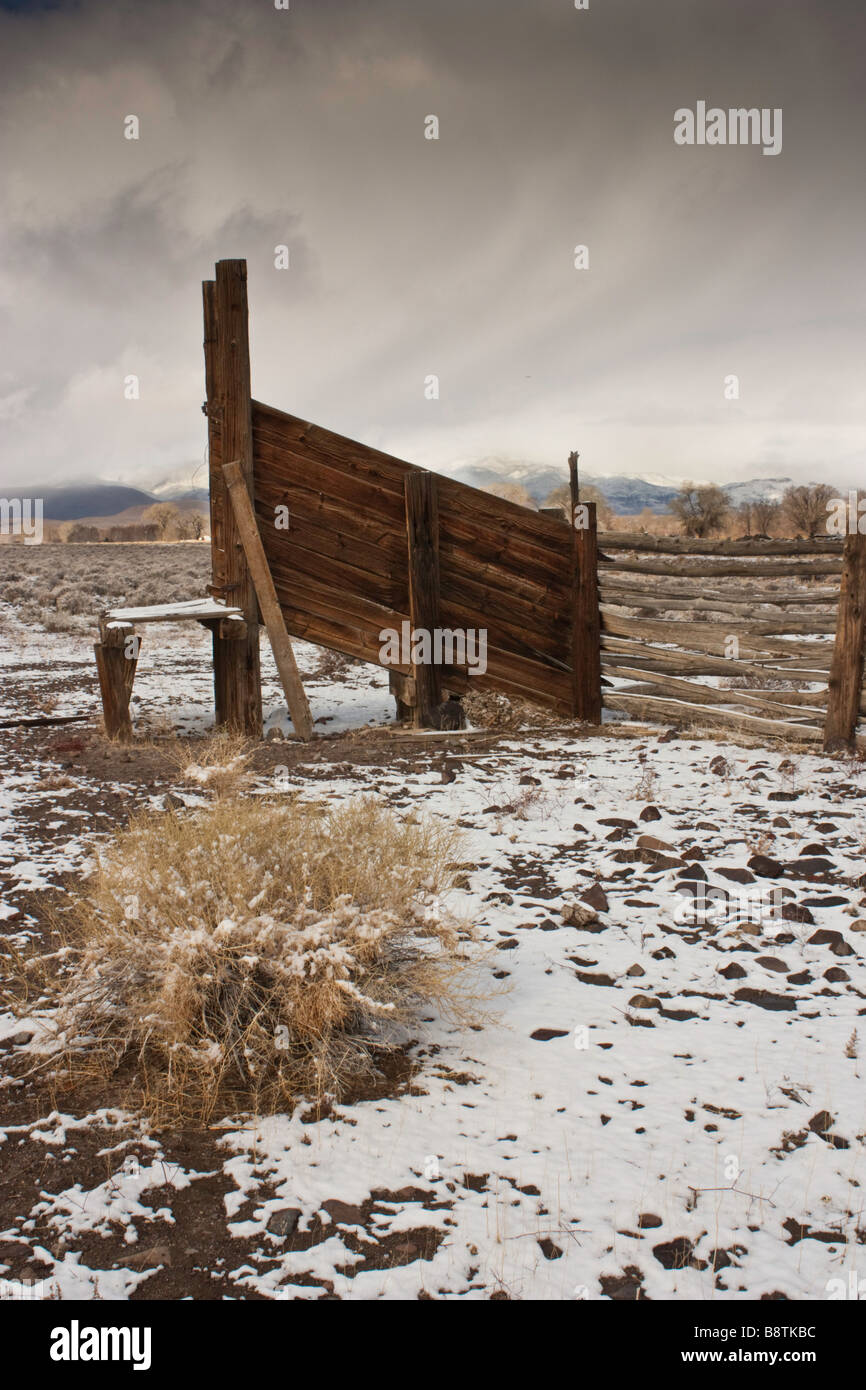 Cattle chute and fence of a rustic old corral with an approaching snow ...