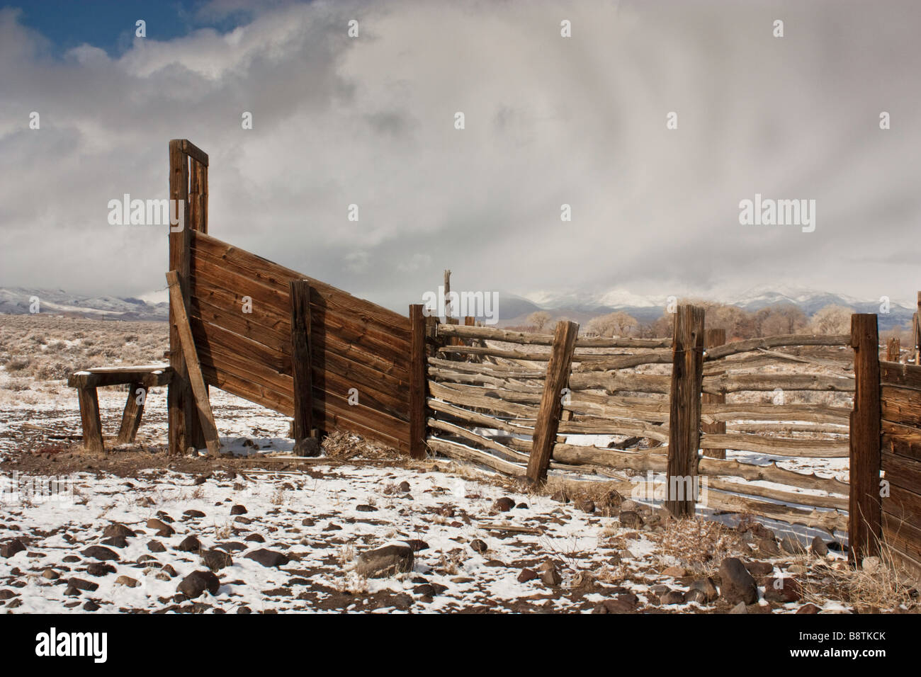Cattle chute and fence of a rustic old corral with an approaching snow ...