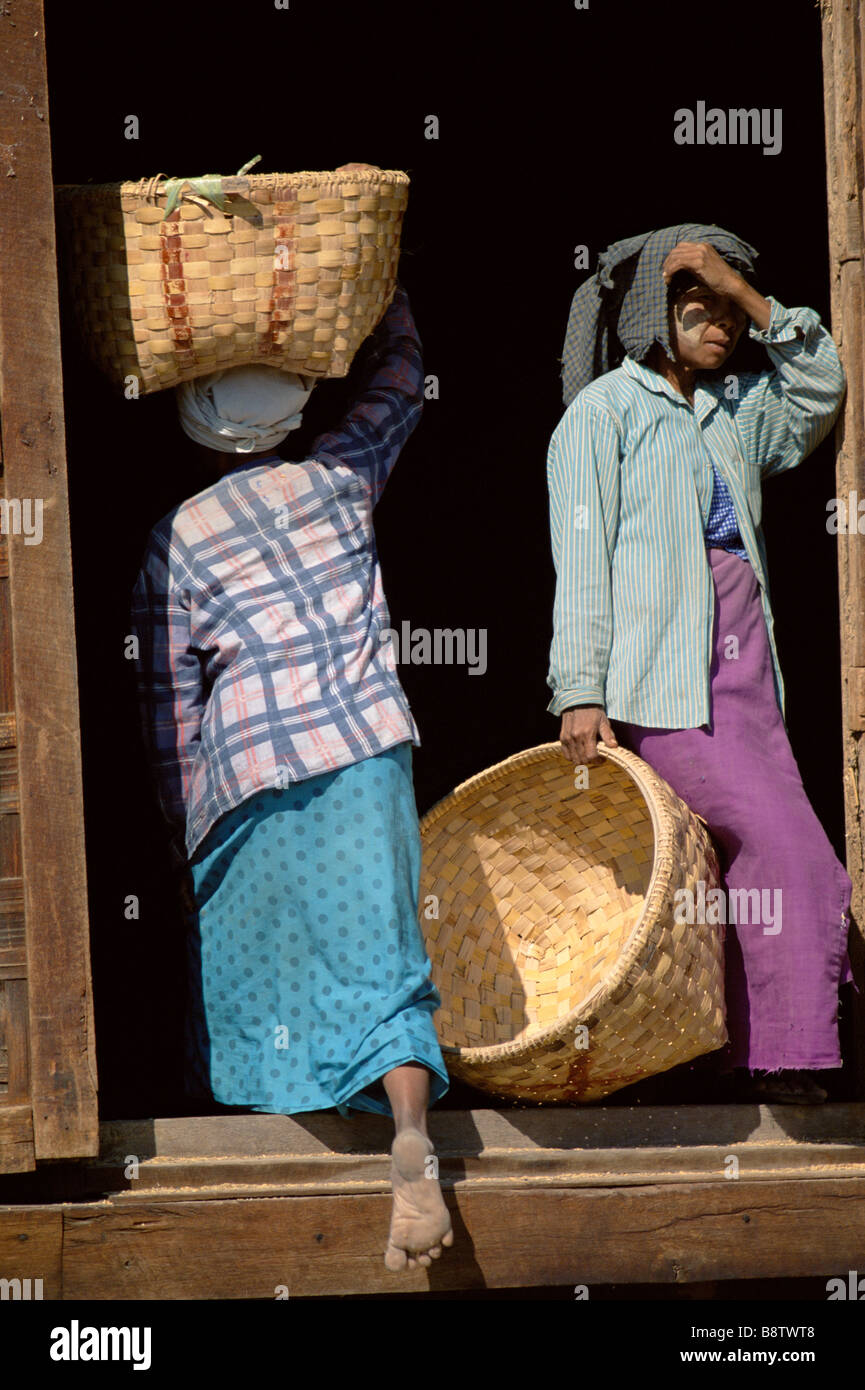 Women carrying baskets of rice into a municipal rice collection point ...