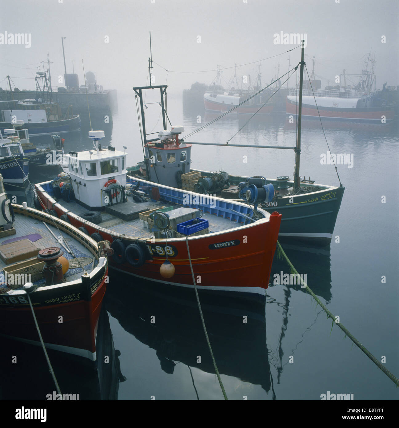 Fishing boats in the harbour at Seahouses with mist on the water Stock Photo - Alamy