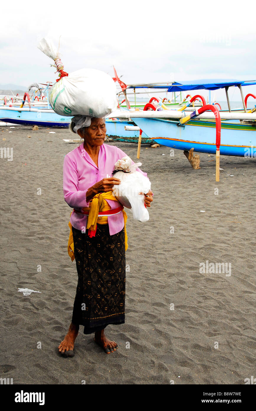 Balinese old lady carrying sack of offering on her head join cremation ...