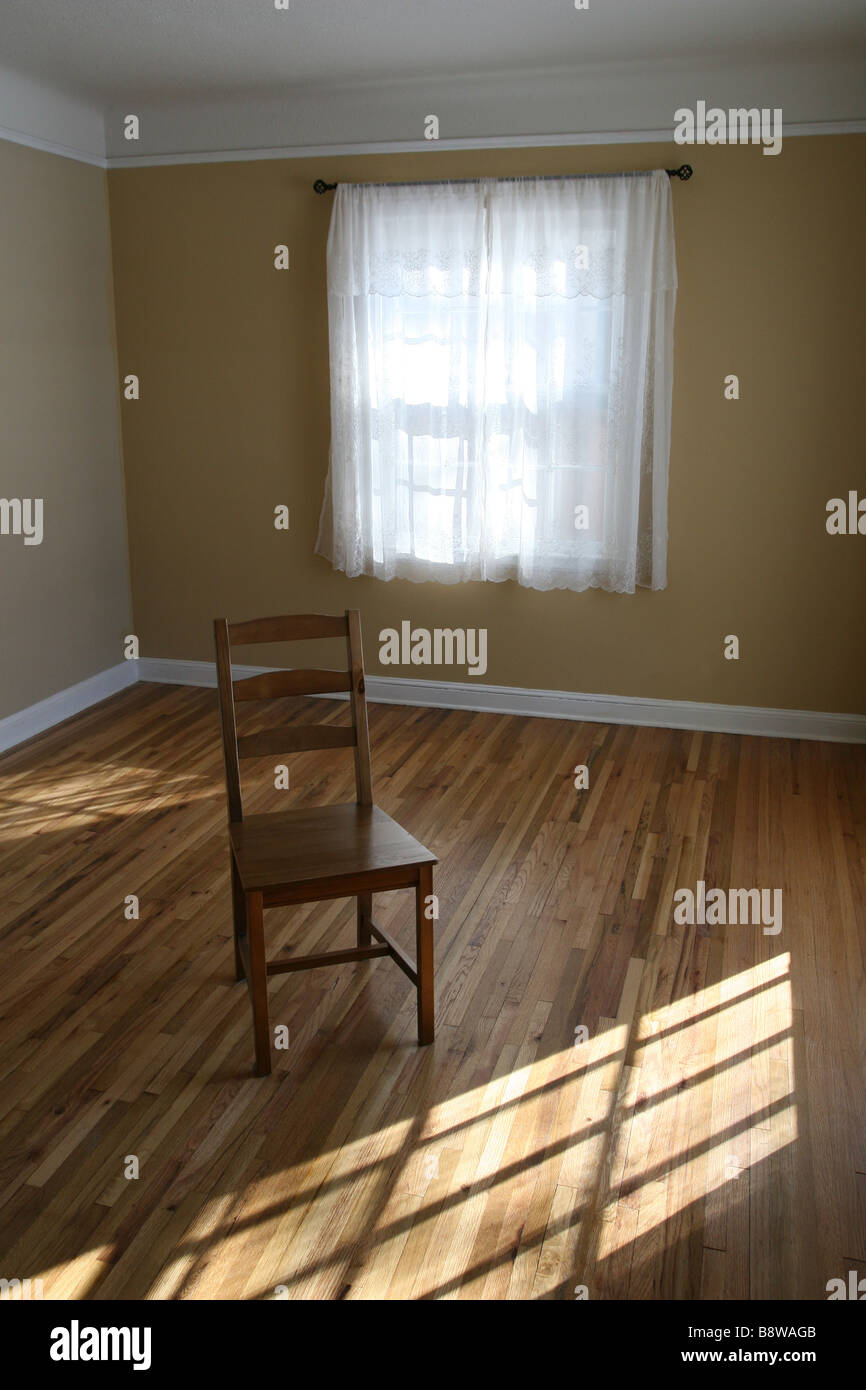 A wooden chair sitting in the middle of an empty room Stock Photo - Alamy