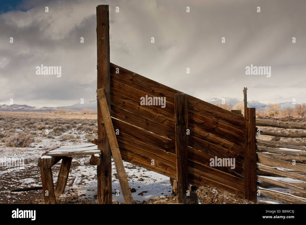 Cattle chute and fence of a rustic old corral with an approaching snow ...