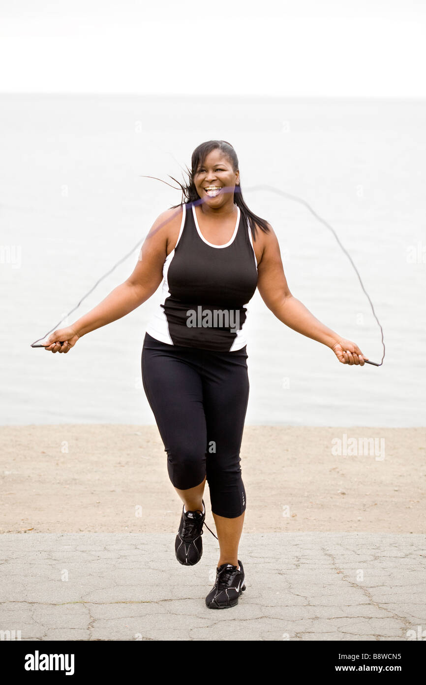 Plus size model jumping rope at a marina park Stock Photo - Alamy
