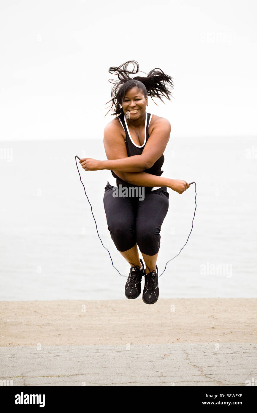Plus size model jumping rope at a marina park Stock Photo - Alamy