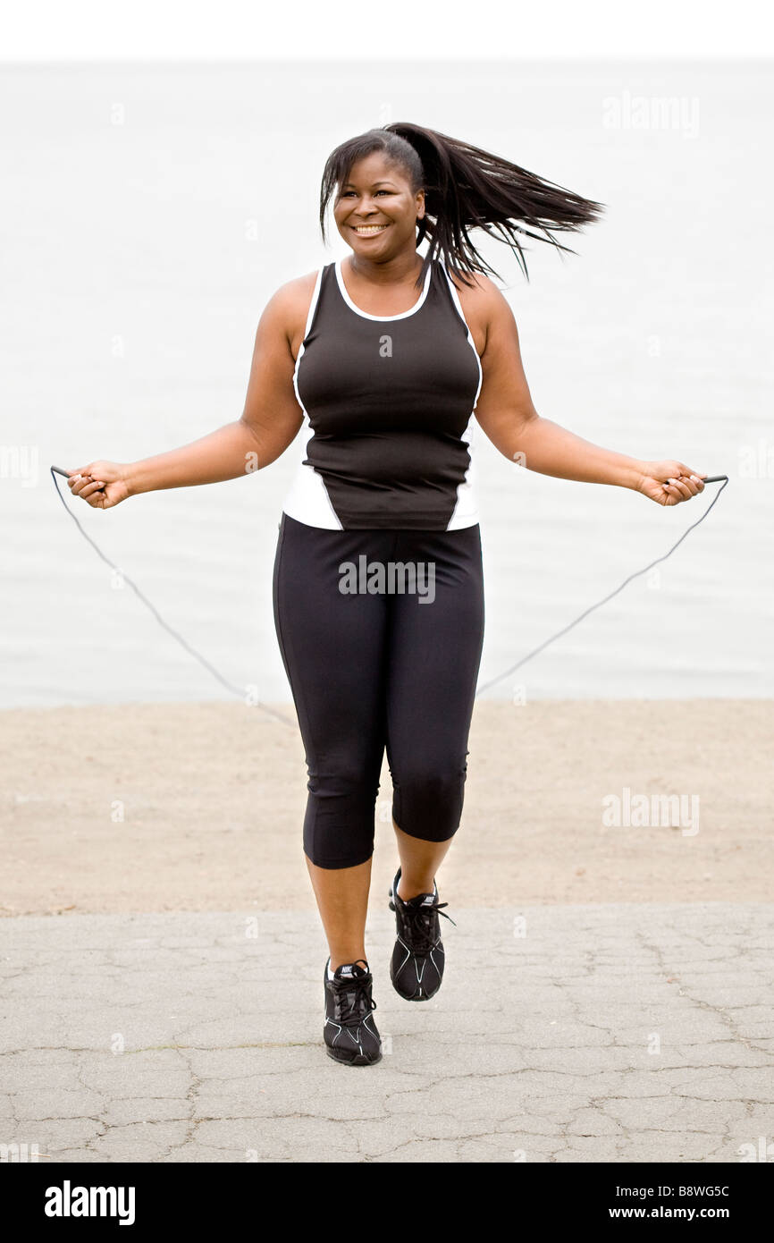 Plus size model jumping rope at a marina park Stock Photo - Alamy