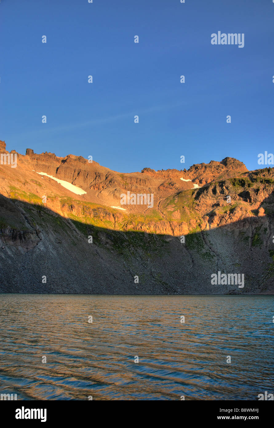 Mountain lake as sunrise lights up a mountain ridge behind it Stock ...